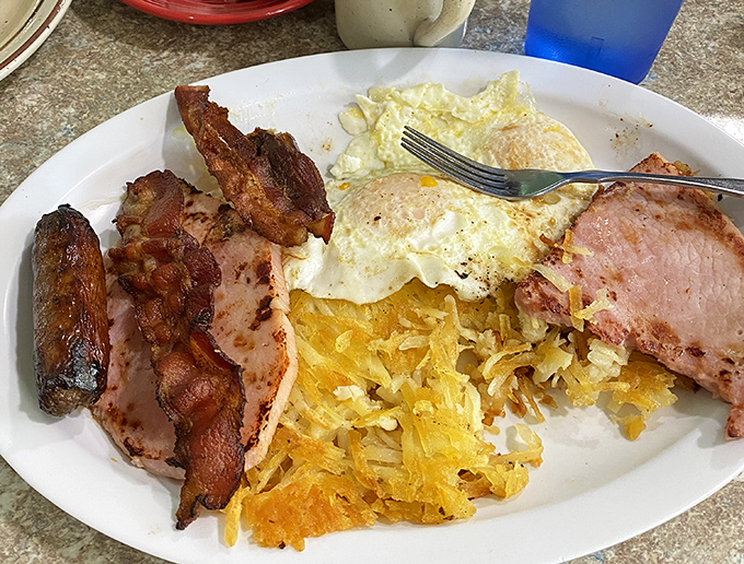 Breakfast of champions: eggs, hash browns, ham, and bacon arranged with the precision of an artist who understands morning hunger is serious business.