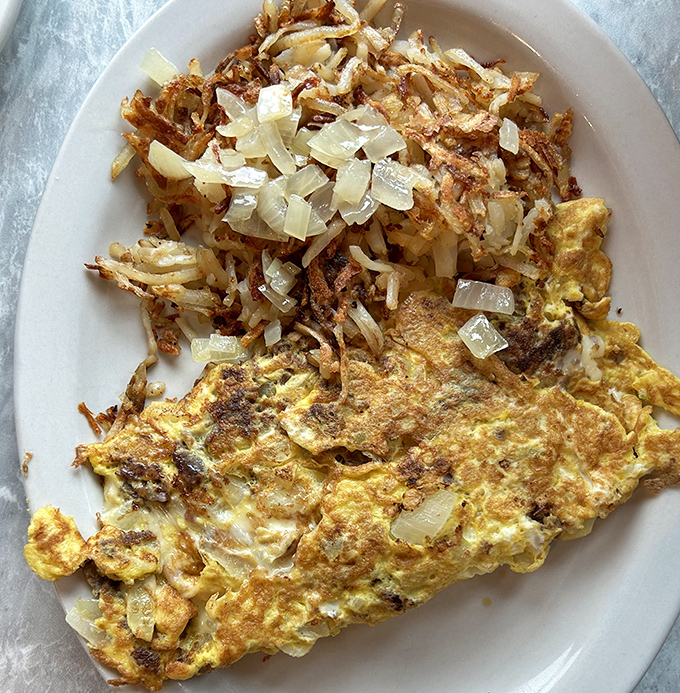 A perfectly executed omelet meets its match in crispy home fries, proving that sometimes the simplest combinations make the most satisfying meals. 