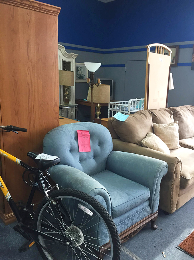 A blue armchair nestled among vintage furniture pieces. Someone's grandmother loved this chair, and now it's ready for your living room stories.