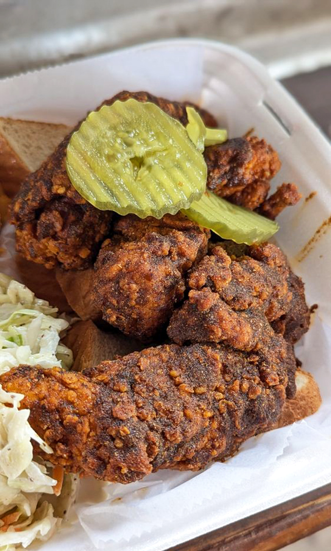 Traditional hot chicken served on white bread with pickle chips&mdash;a time-honored Nashville combination that's both fire and comfort. The coleslaw stands by, ready for emergency cooling duties.