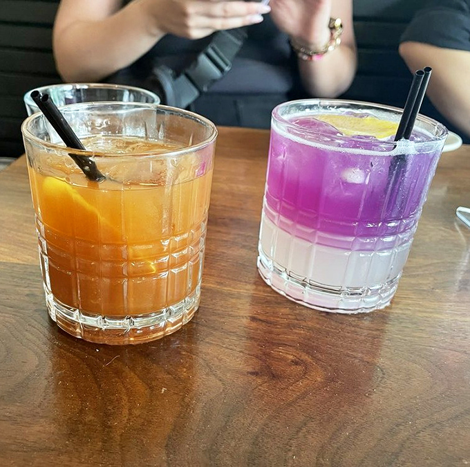 Two cocktails that could double as modern art&mdash;one amber as sunset, one gradient purple that screams "I'm not your average happy hour."