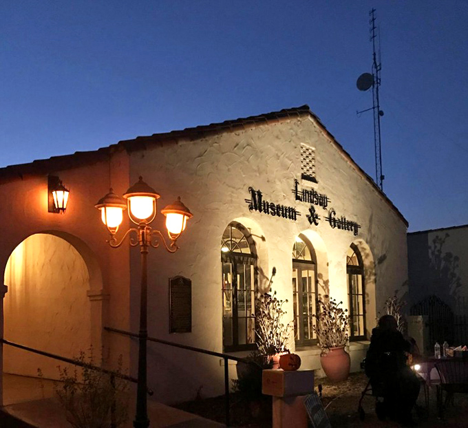 Night transforms the Lindsay Museum & Gallery into a glowing beacon of culture, its Spanish architecture illuminated by vintage lamps.