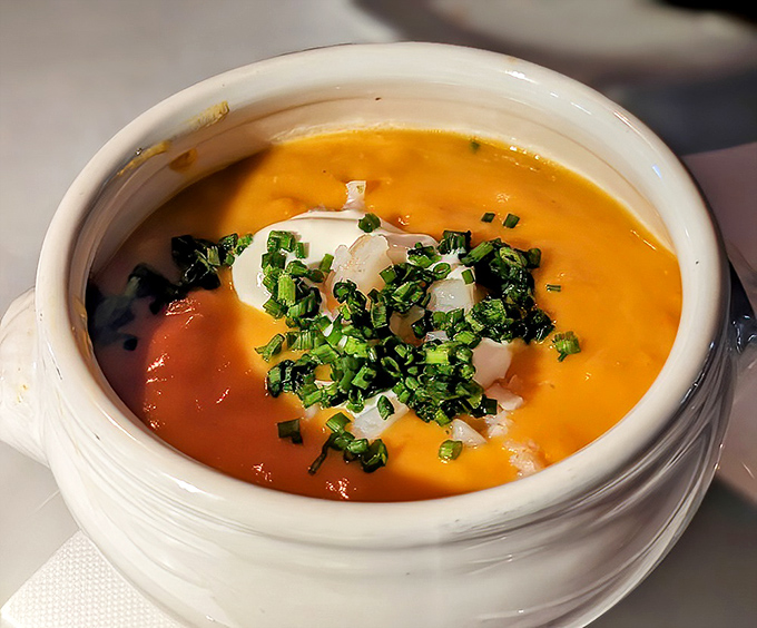 The legendary lobster bisque arrives like liquid velvet—a sunset-colored potion that might actually contain magic.