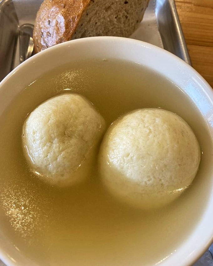 Two matzo balls floating in golden broth like planets in a delicious universe. Chicken soup that could cure anything from colds to existential crises.