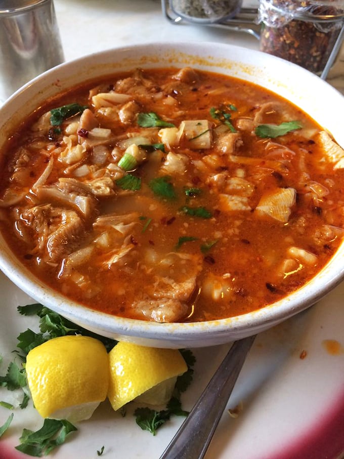 Menudo: the legendary hangover cure that's worth ordering even when you're perfectly fine. Those bright lemon wedges aren't just garnish&mdash;they're essential flavor magic.
