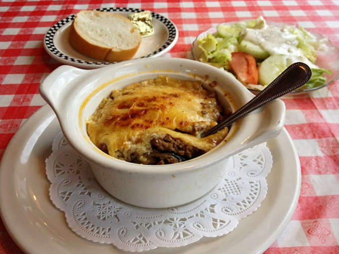 Tucked into a ceramic crock, this bubbling casserole waits patiently on its doily throne, promising warmth that goes beyond mere temperature.