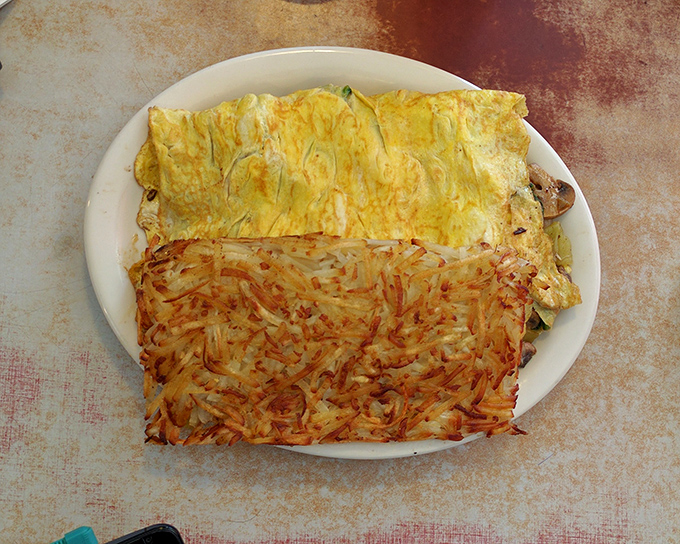 An omelet that's seen things&mdash;namely hash browns that have achieved the perfect crisp-to-tender ratio. Breakfast nirvana on a simple white plate.