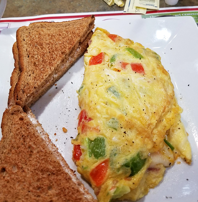 An omelet that doesn't just contain vegetables—it celebrates them, with each colorful pepper and tomato piece getting its moment to shine.