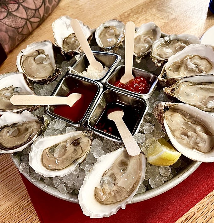A dozen glistening oysters on ice, surrounded by colorful condiments&mdash;nature's perfect appetizer waiting for a squeeze of lemon and a moment of appreciation.