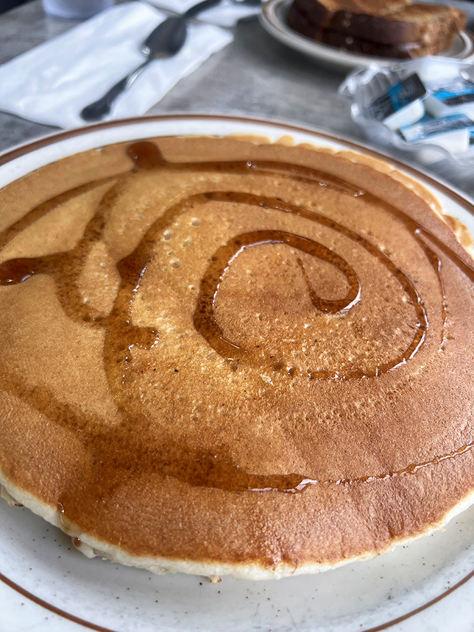 A pancake so perfectly golden and massive it deserves its own ZIP code. Syrup rivers create delicious topography.