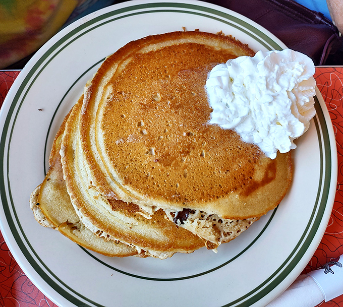 Pancakes so fluffy they practically float off the plate, crowned with clouds of whipped cream.