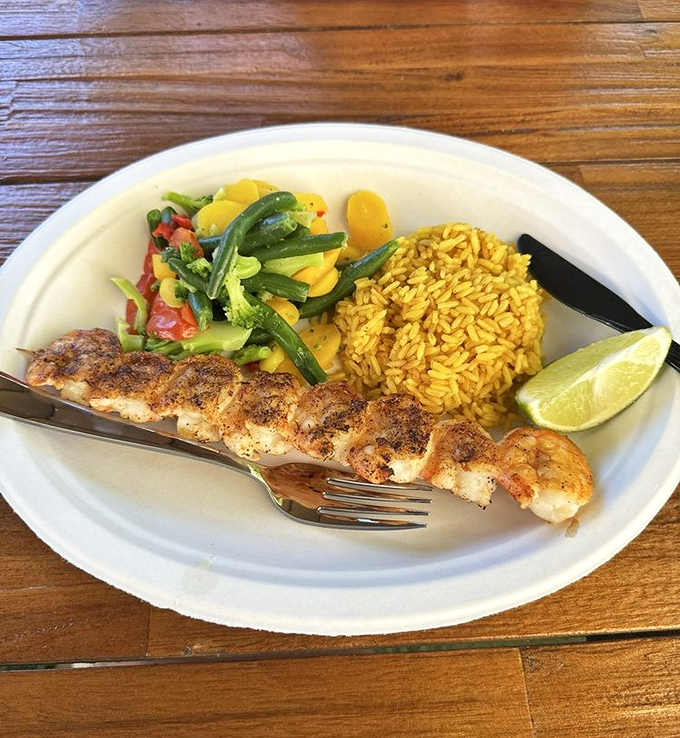 Perfectly grilled shrimp alongside yellow rice and fresh vegetables—proof that paradise can indeed fit on a single plate.
