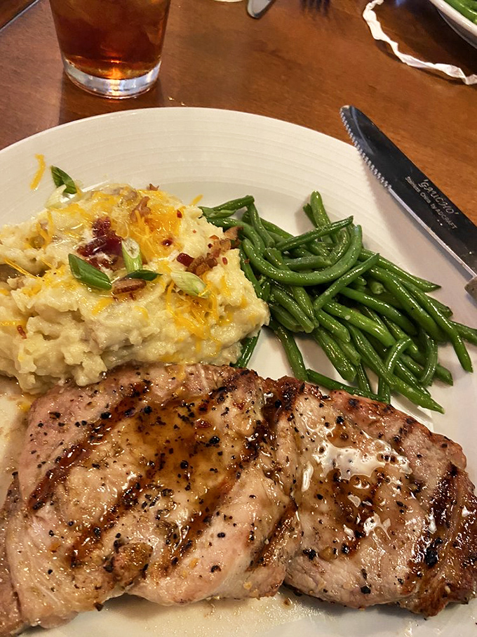 Loaded mashed potatoes that could make a vegetarian question their life choices, alongside green beans and a pork chop that means business.