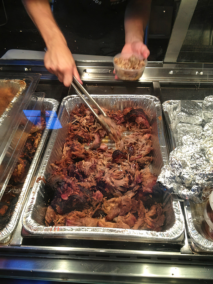 Someone's hands orchestrating the pulled pork symphony&mdash;each strand of meat conducting flavor directly to your taste buds.