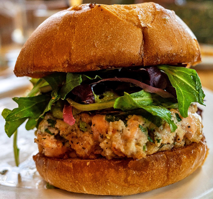 Not just a salmon burger but an architectural marvel—perfectly stacked with vibrant greens on a bun that's achieved the ideal toast-to-softness ratio.