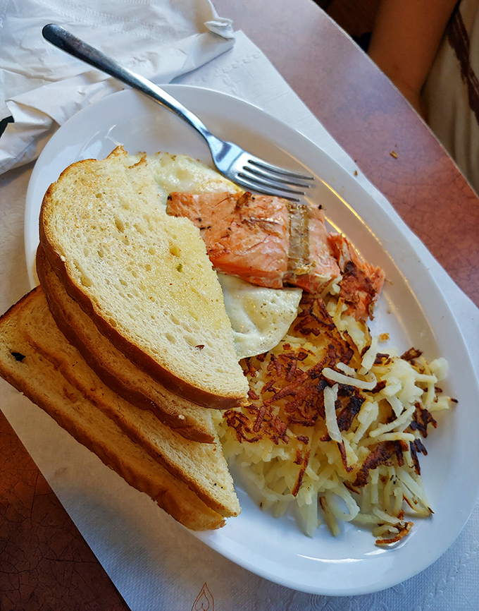 The perfect breakfast trinity: golden toast, crispy hash browns, and salmon that would make upstream swimming seem entirely worth the effort.