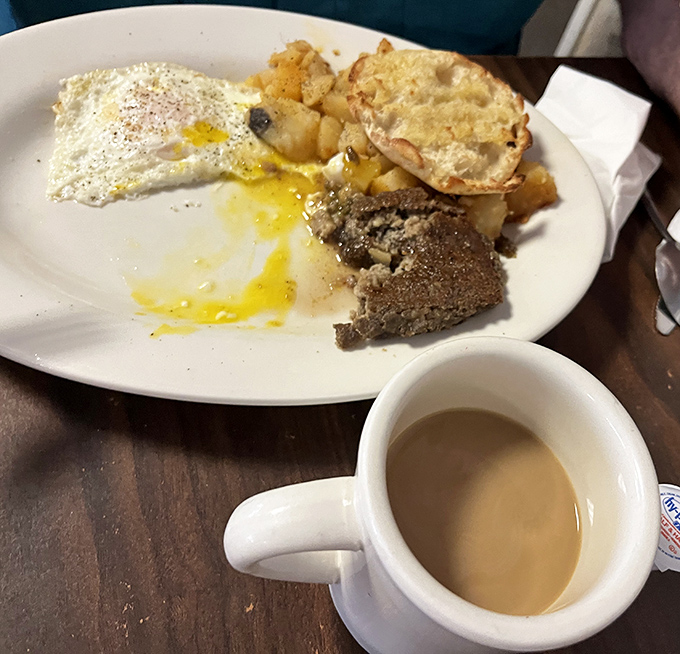The holy trinity of breakfast: runny-yolked eggs, crispy-edged scrapple, and home fries that somehow manage both crispy and tender.