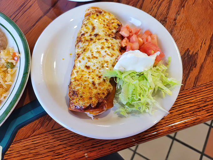 This isn't just any enchilada&mdash;it's a cheese-blanketed envelope delivering a love letter to your taste buds, with diced tomatoes and shredded lettuce for company.