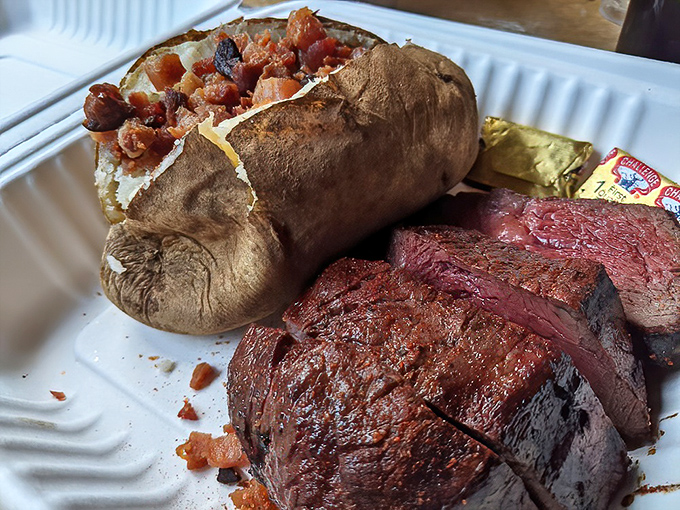 A baked potato loaded like a freight train next to steak with the perfect char&mdash;proof that heaven exists and it tastes like oak smoke.
