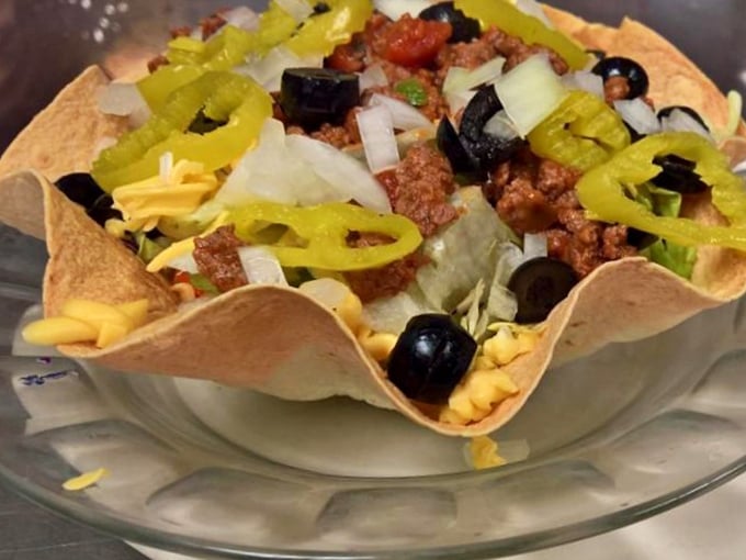 A taco salad that doesn't know it's supposed to be healthy—crispy shell cradling seasoned meat, cheese, and veggies in delicious rebellion.