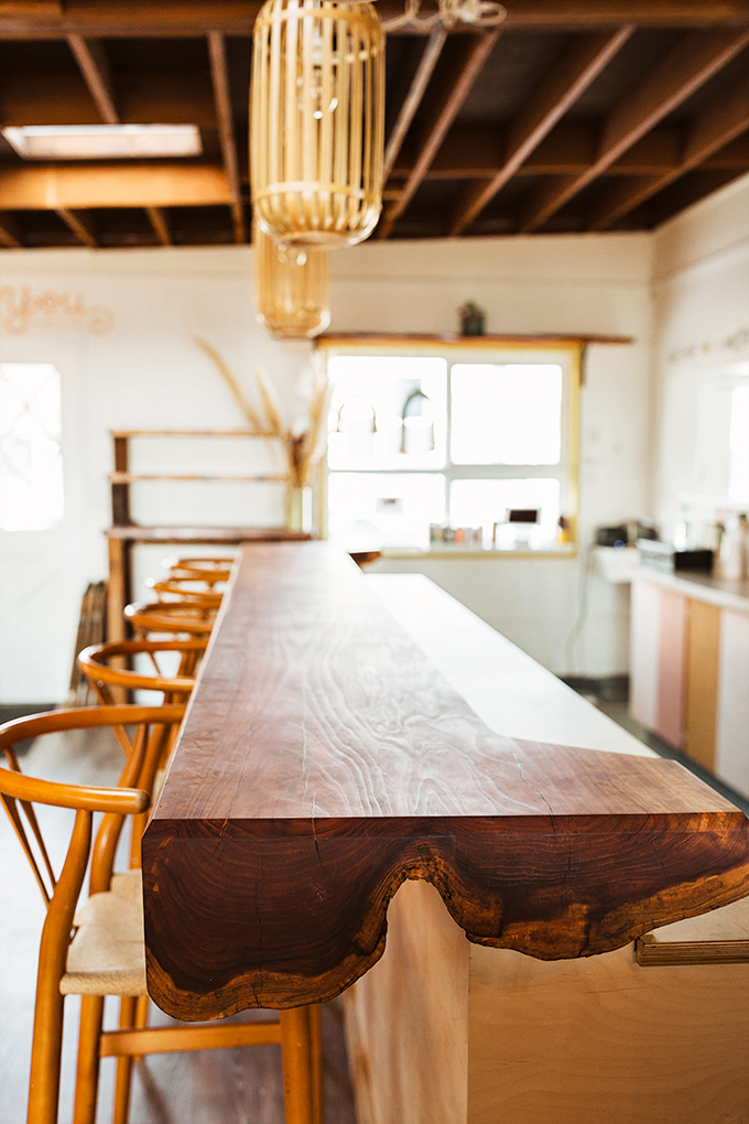 This live-edge wooden bar isn't just furniture; it's a conversation piece where strangers become friends over locally-sourced coffee and coastal views.