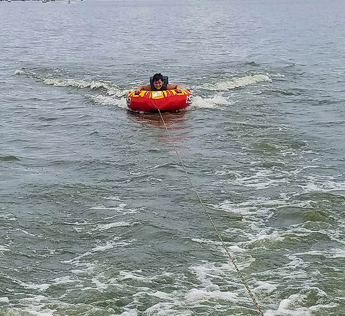 The universal expression of summer joy: a child being pulled across water in an inflatable tube, creating memories that will outlast any sunburn.