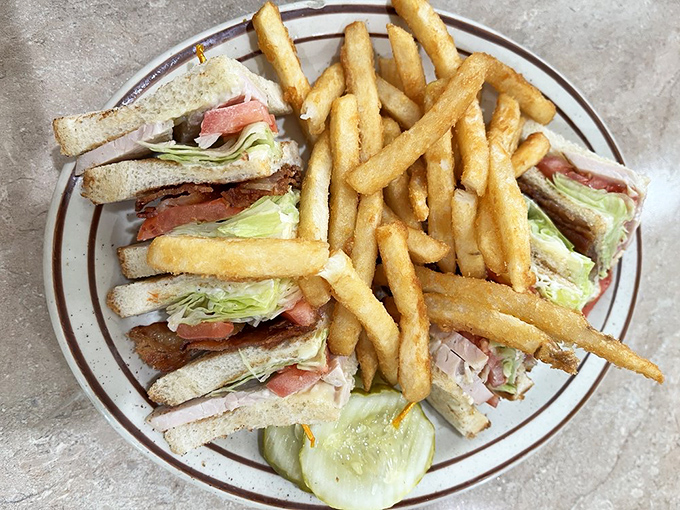 The club sandwich—architecture you can eat. Three stories of deliciousness held together with the structural integrity only toothpicks can provide.