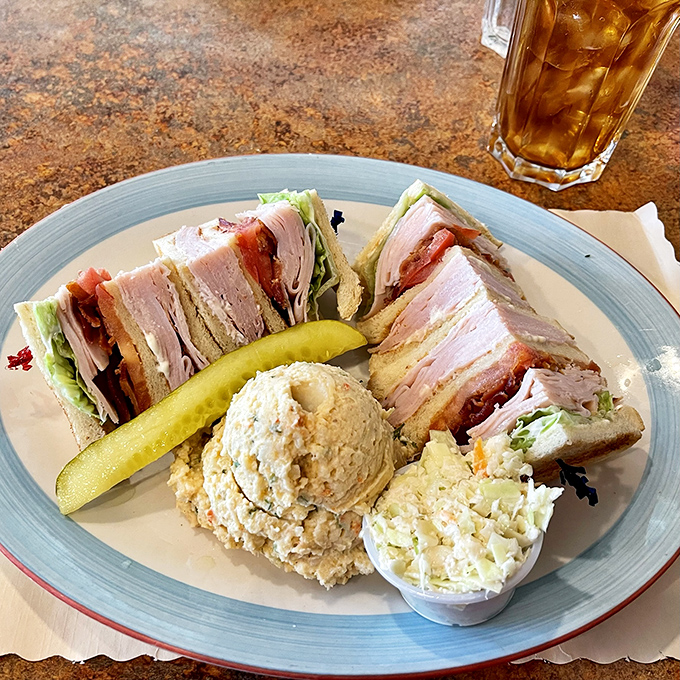 The club sandwich—that three-story monument to lunch perfection where turkey, bacon, and mayo achieve the architectural harmony Frank Lloyd Wright could only dream about.