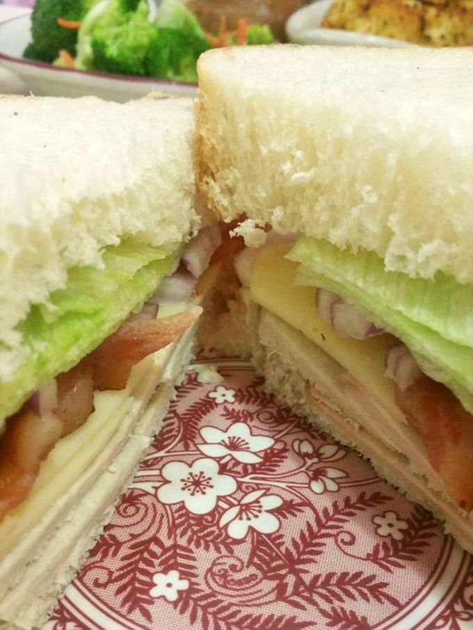 This sandwich isn't just stacked&mdash;it's architecturally sound. White bread, fresh veggies, and layers of deli meat creating the Taj Mahal of lunch.