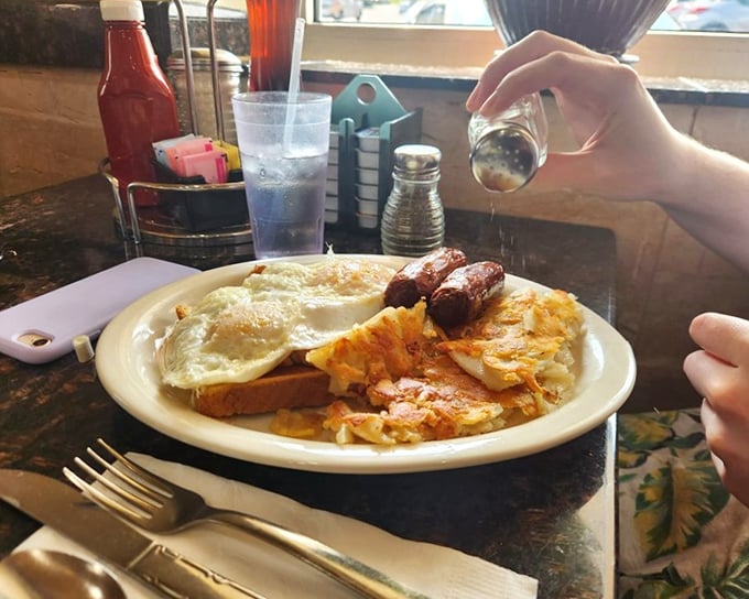 The breakfast trinity: perfectly cooked eggs, savory sausage links, and those home fries that could make a potato farmer weep with pride.