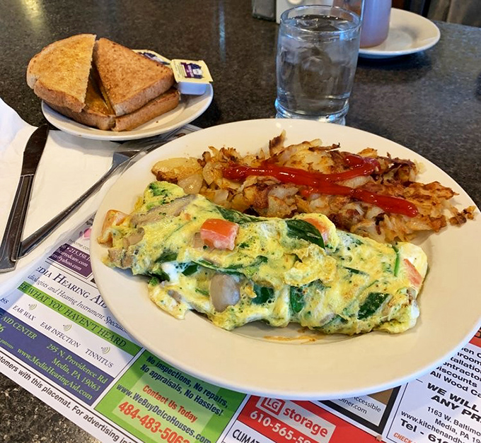 An omelet stuffed with more vegetables than most people eat in a day, paired with home fries that demand a ketchup drizzle.