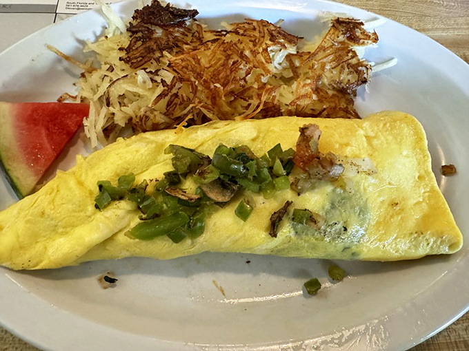 An omelet that's having a meaningful relationship with those hash browns. The watermelon slice adds that perfect sweet counterpoint.