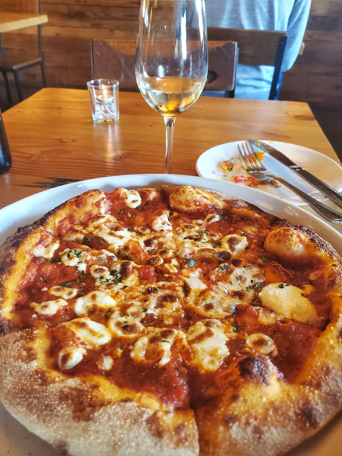 Pizza and wine: civilization's greatest pairing since Holmes and Watson. The char on that crust deserves its own fan club.