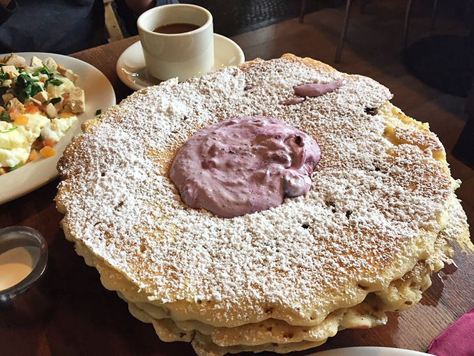 Behold the pancake mothership: a golden disc the size of a hubcap, dusted with sugar and crowned with berry-infused cream.