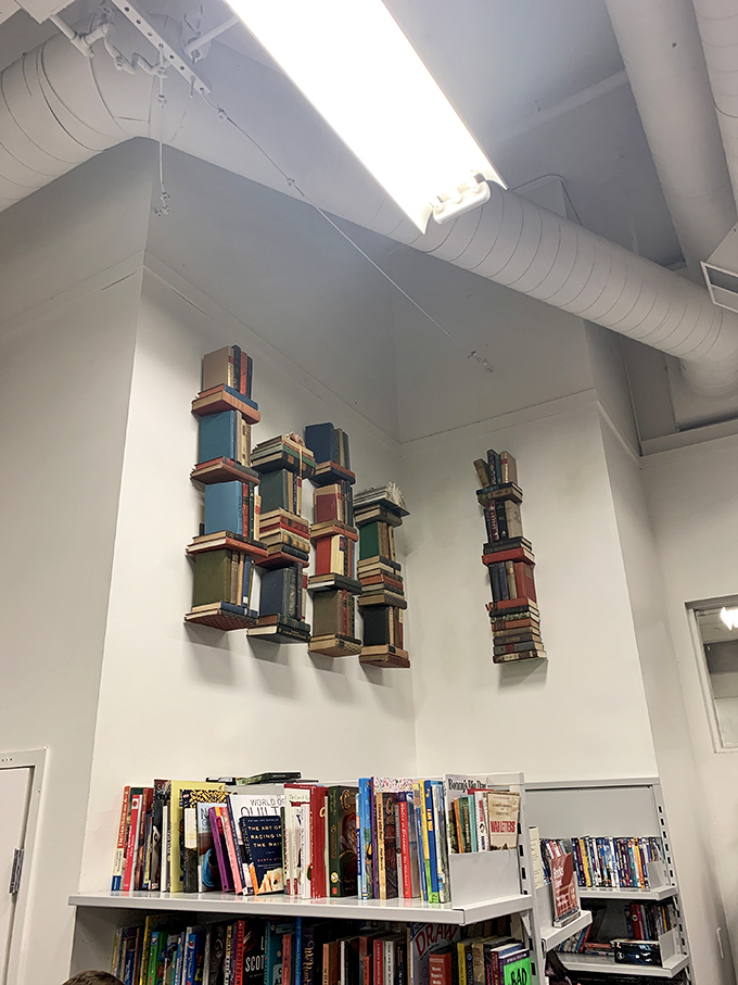 Literary treasures stack high beneath whimsical book art that transforms reading into three-dimensional poetry.