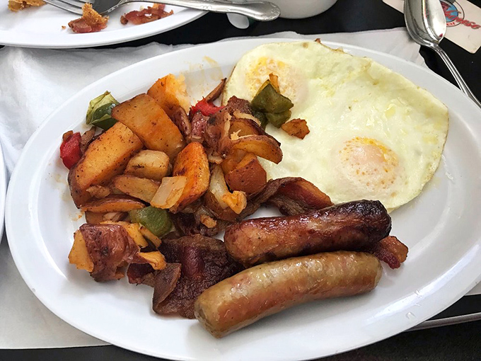 The breakfast trinity: perfectly cooked eggs, savory sausage links, and home fries that could make a potato farmer weep with pride.