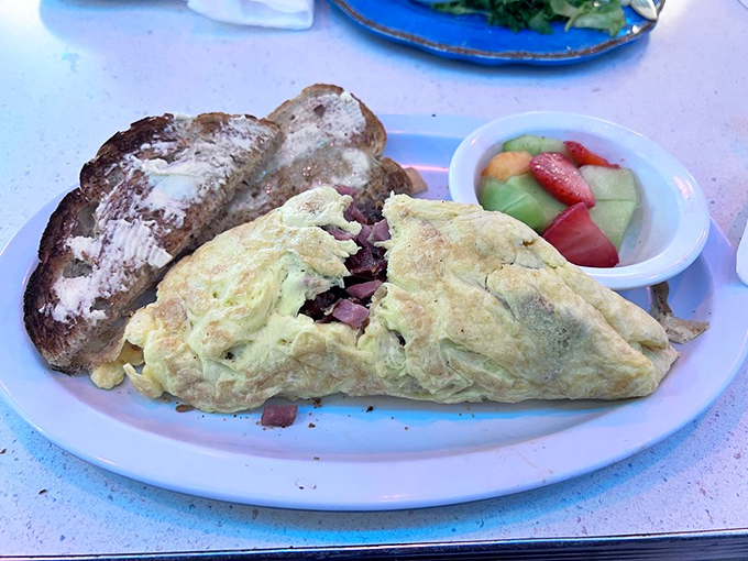 Behold: the omelet that launched a thousand return visits. Fluffy egg perfection with a supporting cast of toast and fresh fruit that knows its role.