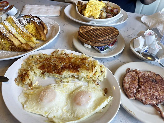 The breakfast spread that launched a thousand food dreams. Sunny-side eggs, perfectly crisped hash browns, and sausage links that snap with satisfaction.
