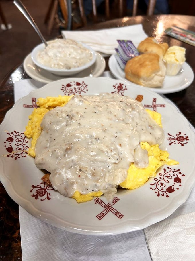 Breakfast nirvana achieved: scrambled eggs blanketed in sausage gravy on a plate adorned with Pennsylvania Dutch windmills. The biscuits are just showing off at this point.