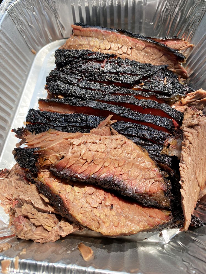 Brisket with a smoke ring so perfect it could be framed in a museum. The pepper-crusted bark is like edible armor protecting treasure within.