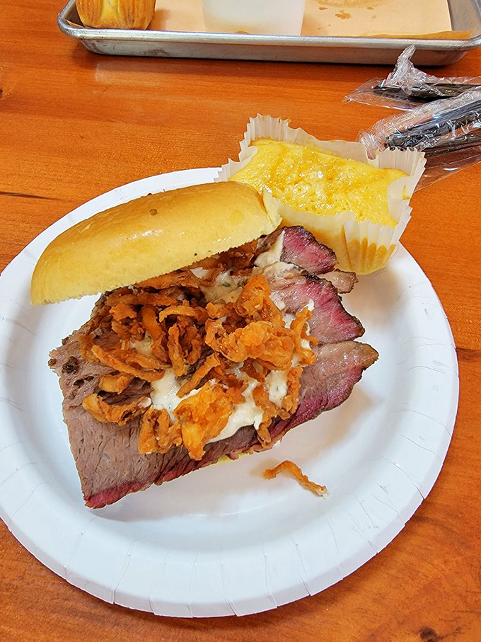 The brisket sandwich that launched a thousand road trips, topped with crispy onions and served with cornbread that demands equal attention.