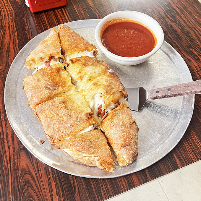 The calzone, cut open to reveal its molten interior, is like pizza that decided to wrap itself in a warm blanket of dough.