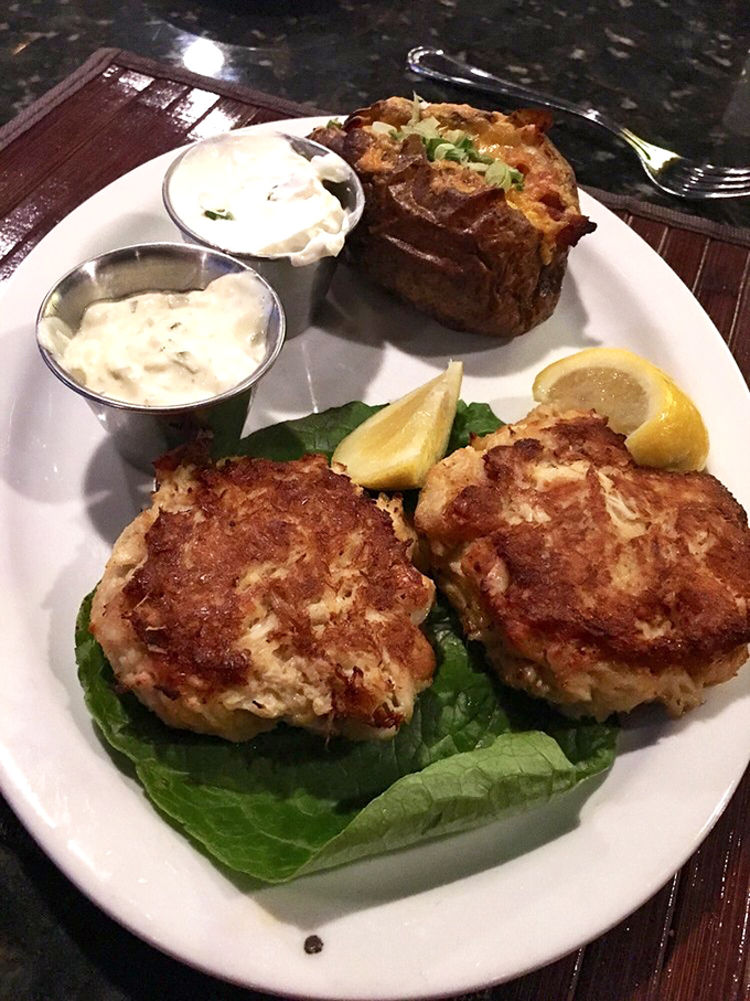 Golden-brown crab cakes perched on crisp lettuce with two dipping sauces standing by. These aren't just appetizers—they're the opening act of a seafood symphony.