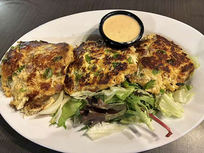 These golden-brown crab cakes are the reason people drive across state lines, sitting pretty on a bed of fresh greens with a side of heaven.