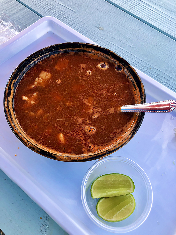 This isn't just soup—it's liquid treasure. Rich seafood broth with chunks of seafood, served with lime wedges for that essential citrus kick.