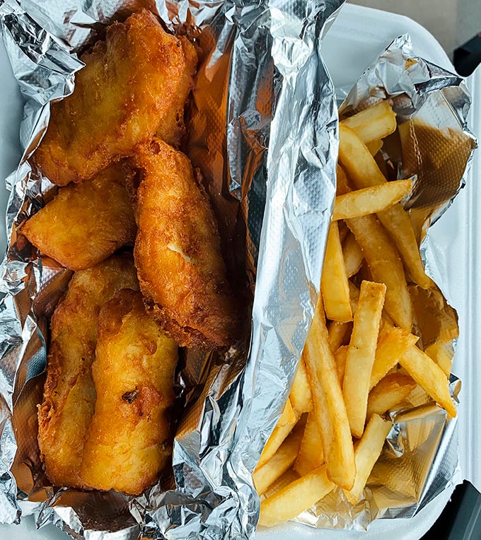 Golden-battered fish and chips that crackle with each bite, served in a takeout container that barely contains their glory. The perfect marriage of crispy and tender.