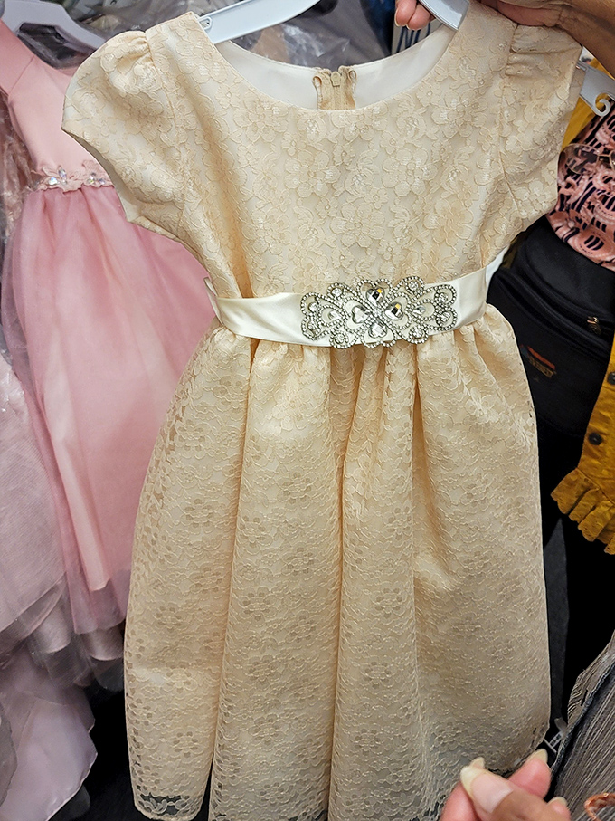 Childhood dreams woven into fabric and lace. This cream-colored dress awaits its princess, ready for a special day of twirls and memories.