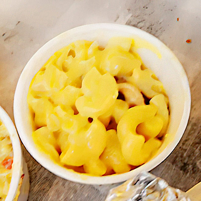 Mac & cheese that glows with the promise of comfort, a creamy counterpoint to the smoky intensity of the main attraction. 