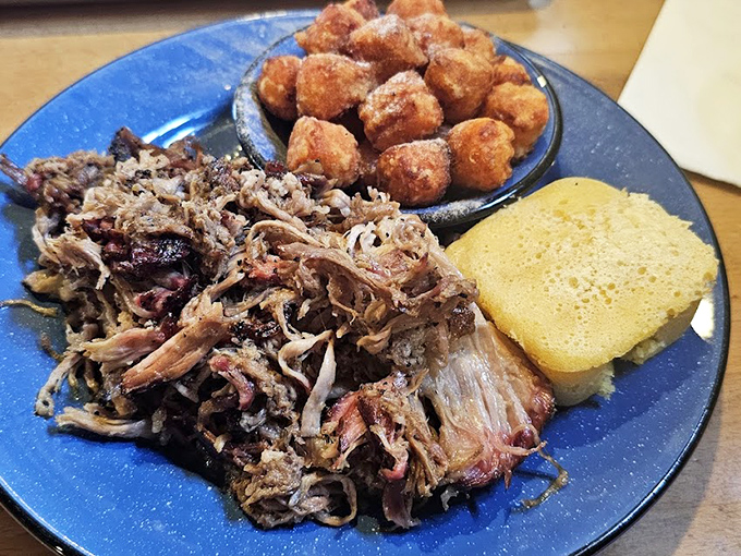 Pulled pork that's had a proper introduction to smoke and patience. Those sweet hush puppies aren't just sides&mdash;they're essential supporting characters in this delicious story.