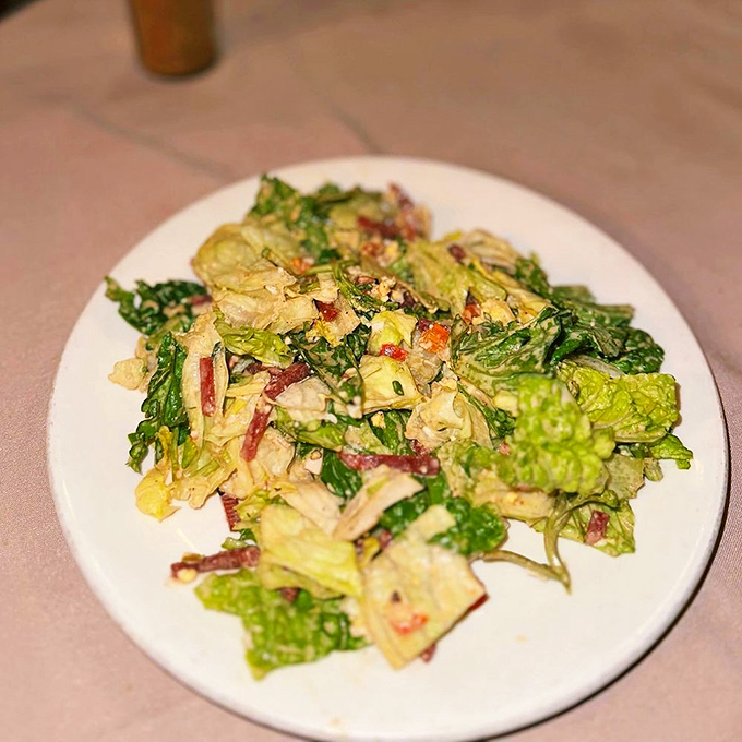 The famous spinning salad bowl presentation transforms simple greens into dinner theater. Somehow, watching its creation makes each bite taste even better.